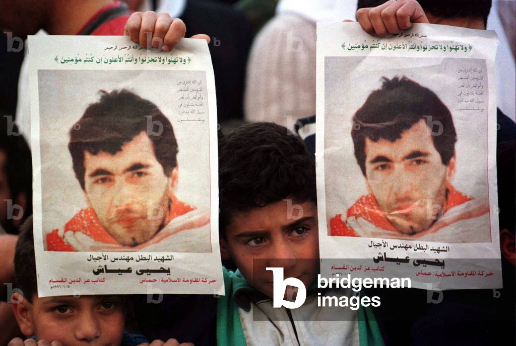 Image of A Palestinian boy holds up posters of Yahya Ayyash at