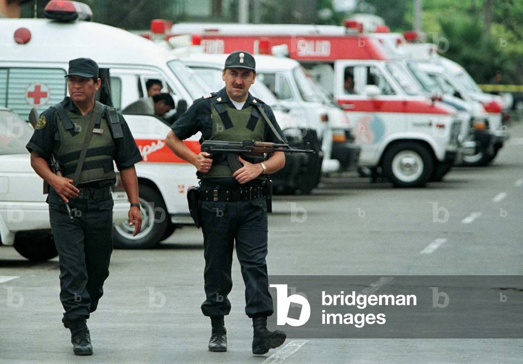 Image of Peruvian elite police walk past a row of ambulances on