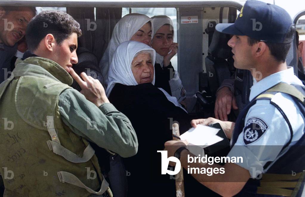 Image of Israeli police check the identity documents of Palestinians at a