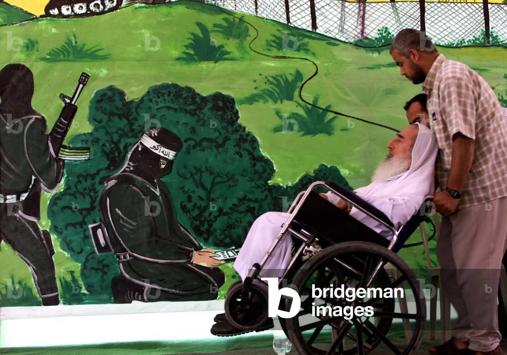 Image of Hamas founder Sheikh Ahmed Yassin is helped past a wall