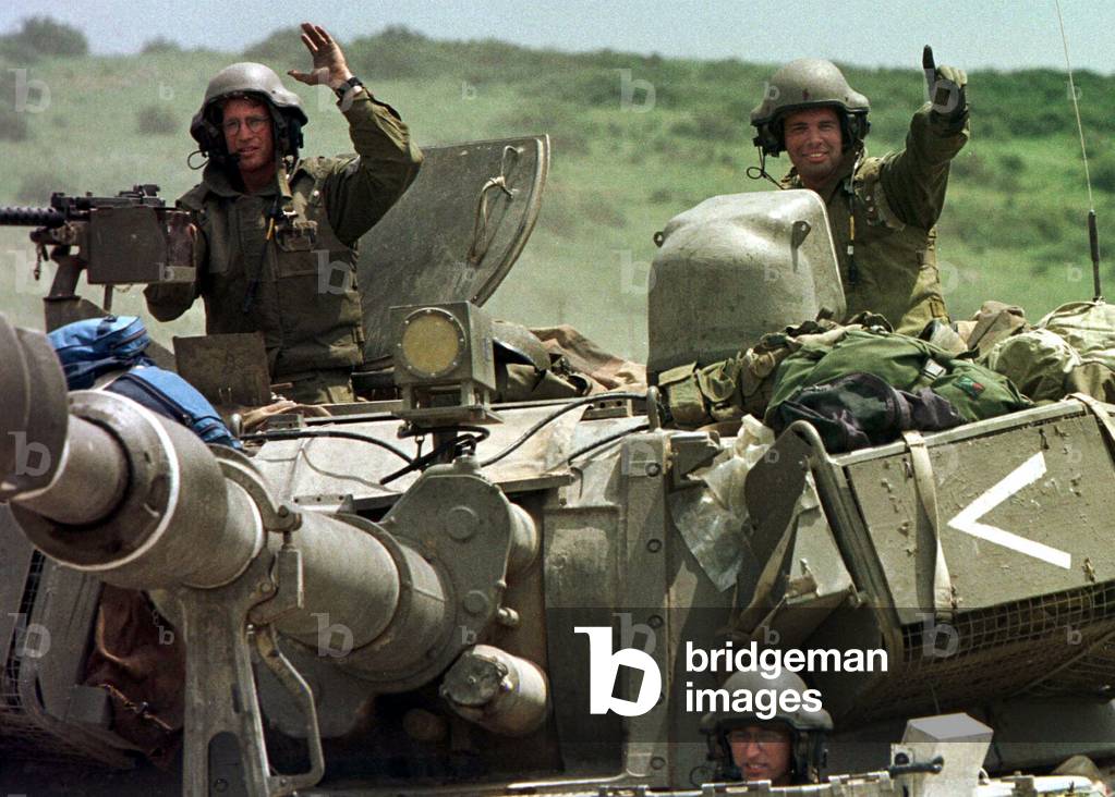 Image of Soldiers atop an Israeli 155mm artillery gun wave as it