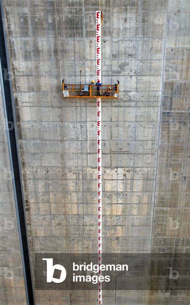 Image of CHINESE CONSTRUCTION WORKERS INSPECT THE WATERMARK ON A MAIN DAM