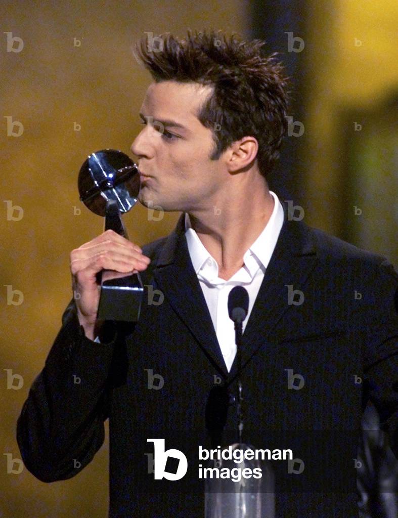 Image of Singer Ricky Martin kisses the Billboard Music Award he won