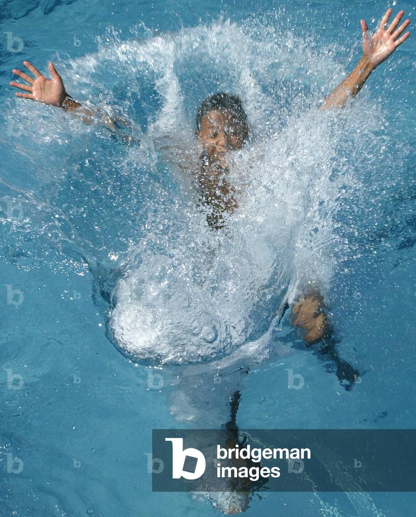 Image of BOY JUMPS INTO A POOL AT A PUBLIC BATH IN