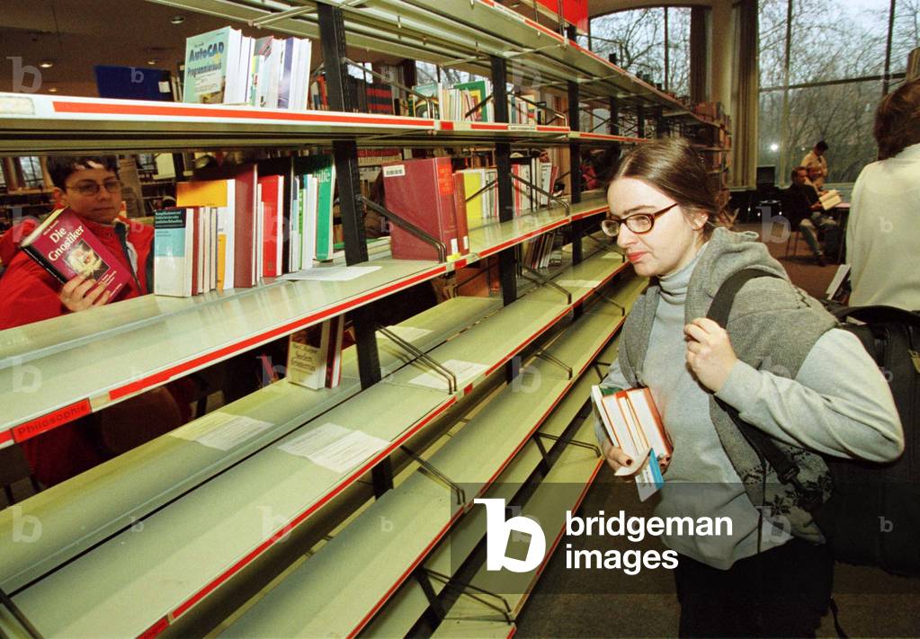 Image of STUDENT PASSES EMPTY SHELVES INSIDE A LIBRARY IN BERLIN, 1997 ...