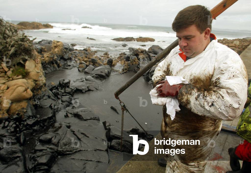Image of A worker wipes oil off himself after positioning a suction