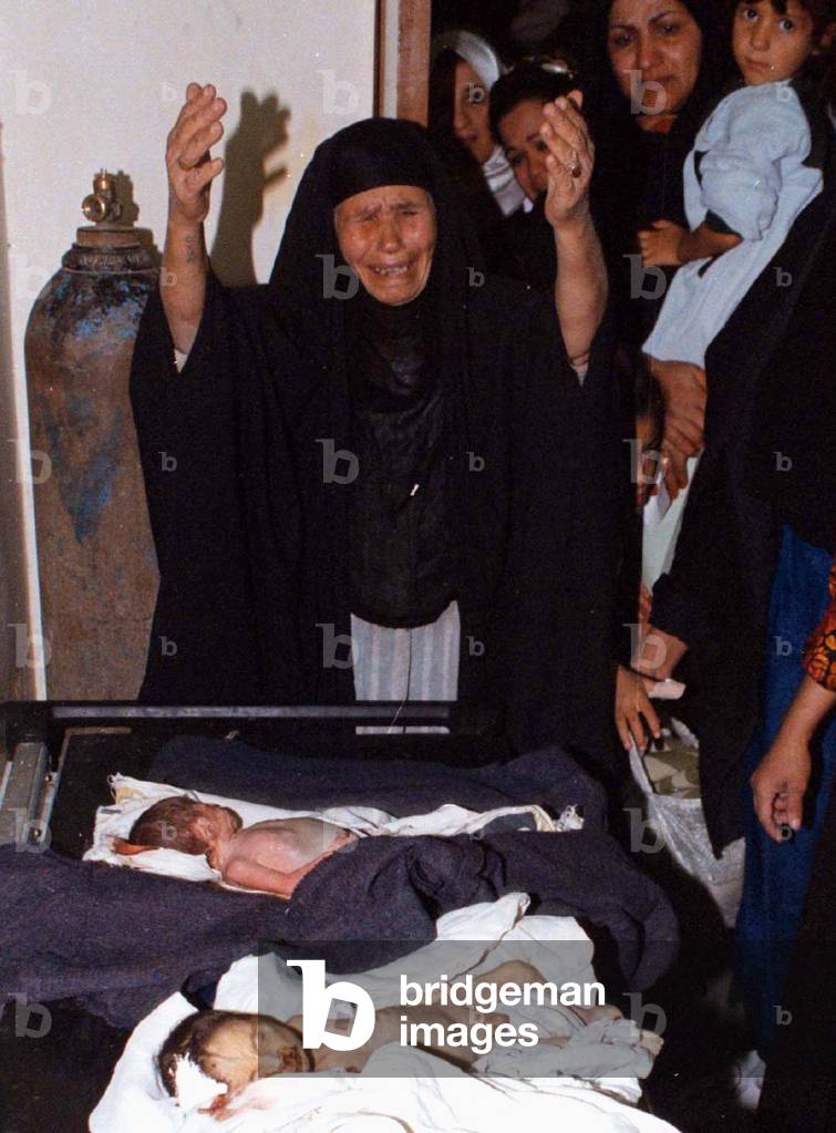 Image of IRAQI WOMAN CRIES OVER THE BODIES OF CHILDREN IN BAGHDAD,