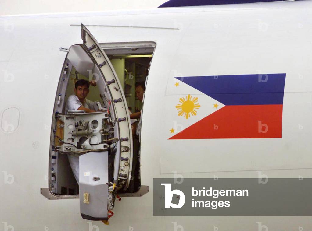 Image of FILIPINO WORKERS INSPECT A REAR DOOR OF A PHILIPPINE AIRLINES