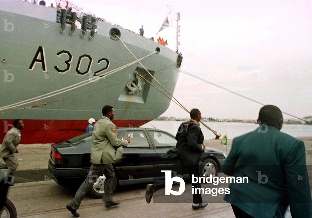 Image of Bodyguards run along side the car of Zairian President Mobutu
