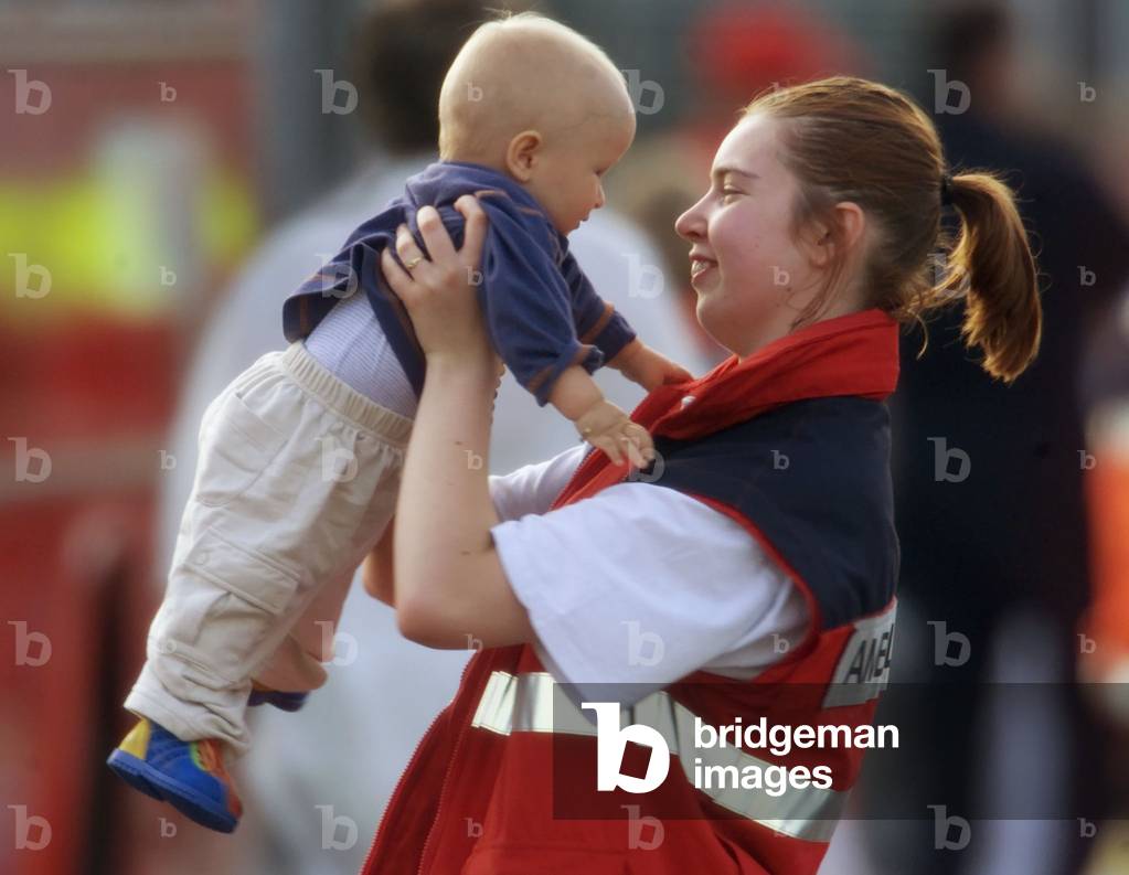 Image of A rescue worker takes care of a little child after