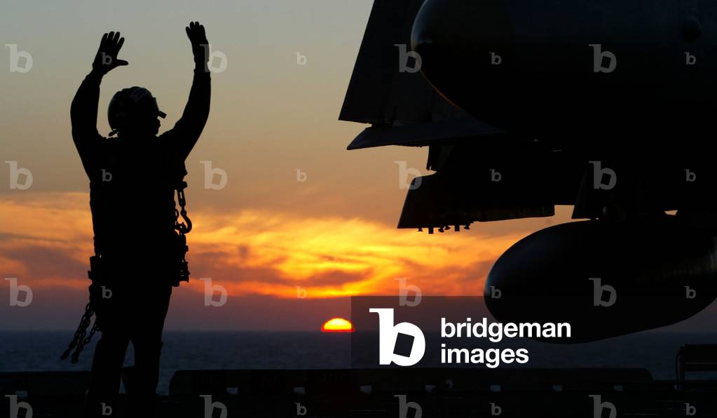 Image of The sun sets as a plane captain signals to the