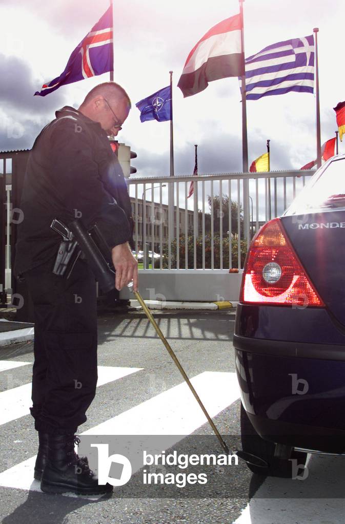 Image of A SECURITY GUARD USES A MIRROR TO INSPECT THE CHASSIS