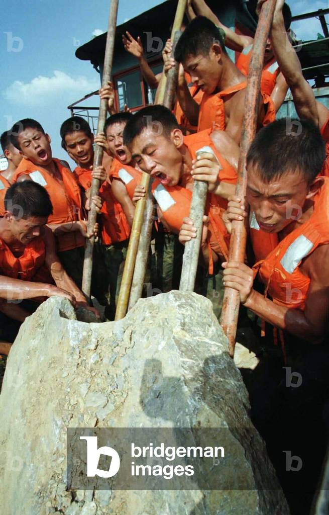 Image of CHINESE SOLDIERS SHIFT A ROCK TO REPAIR A BROKEN DIKE