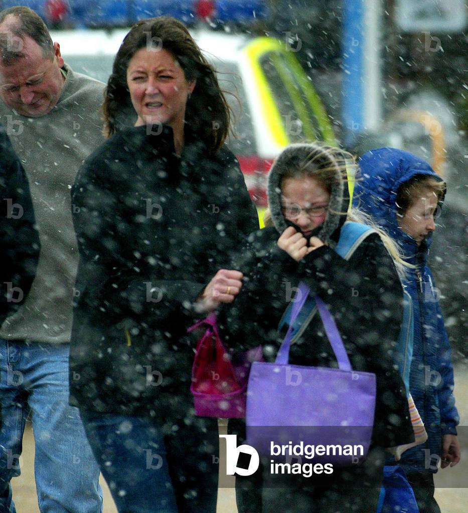 Image of AN UNIDENTIFIED MAN WOMAN AND CHILDREN WALK THROUGH FALLING SNOW