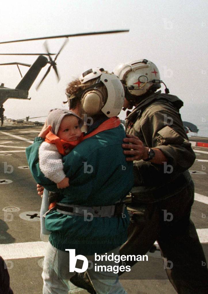 Image of A baby is carried by its mother aboard the USS