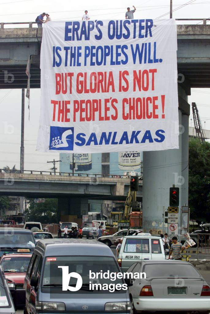 Image of FILIPINO COMMUTERS LOOK AT A HUGE STREAMER IN MANILA, 2001-01-22