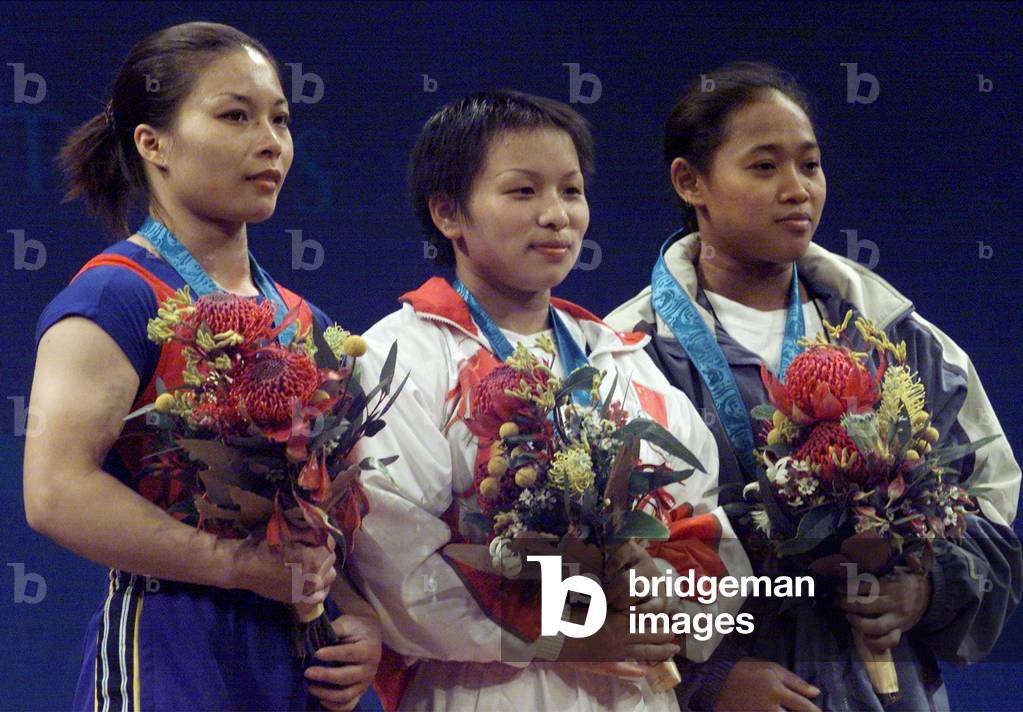 Image of THE WOMEN'S WEIGHTLIFTING MEDALISTS LINE UP ON THE PODIUM IN