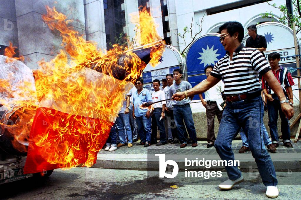 Image of Local celebrity former police officer Benjamin Afuang (R) burns a