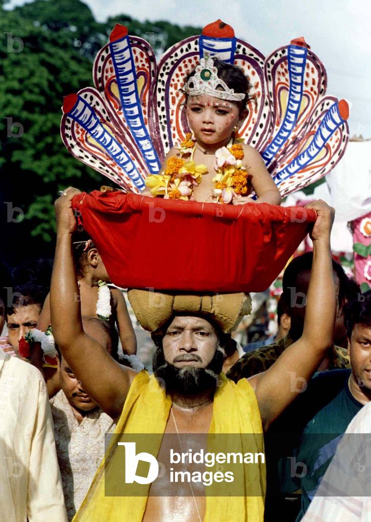 Image of HINDU DEVOTEE CARRY A YOUNG LORD KRISHNA ON HIS SHOULDERS