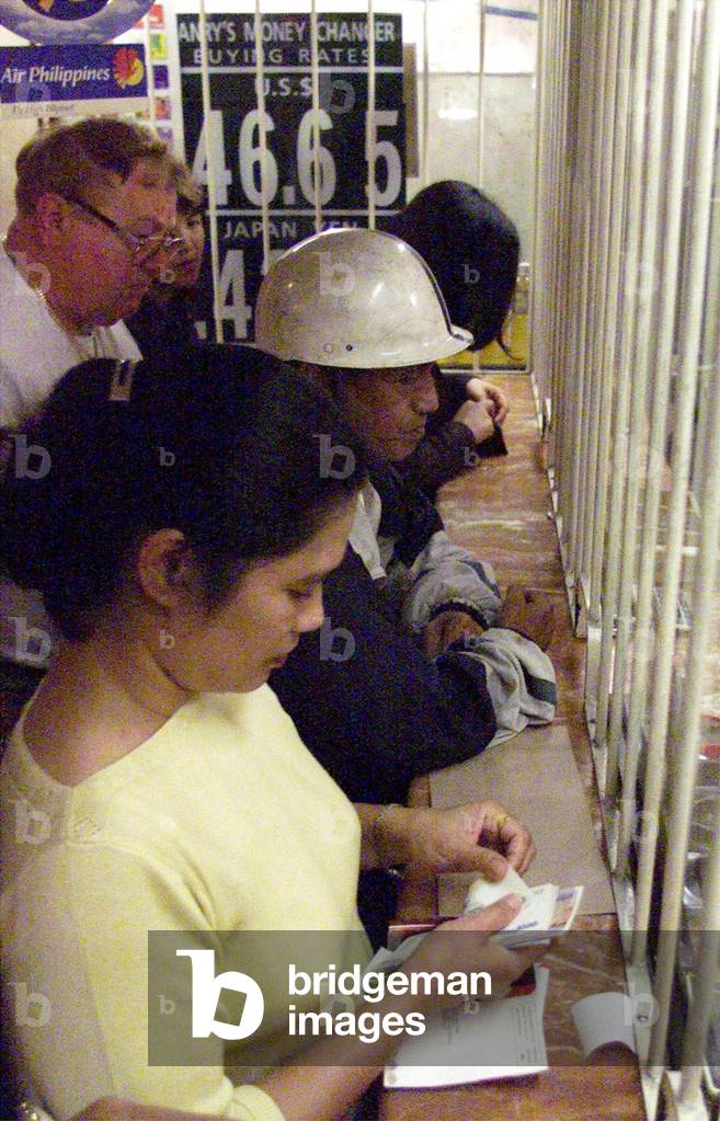 Image of A FILIPINO WOMAN COUNTS PHILIPPINE PESO BILLS INSIDE A MONEY