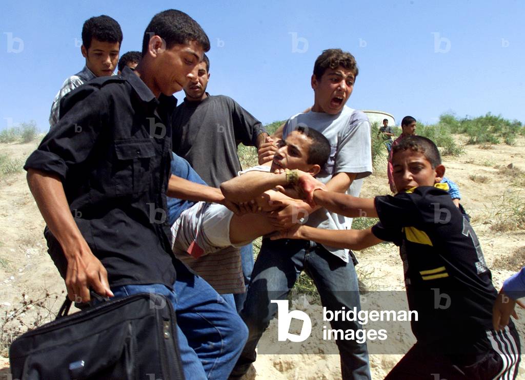 Image of AN INJURED PALESTINIAN BOY IS CARRIED DOWNHILL AFTER BEING HIT