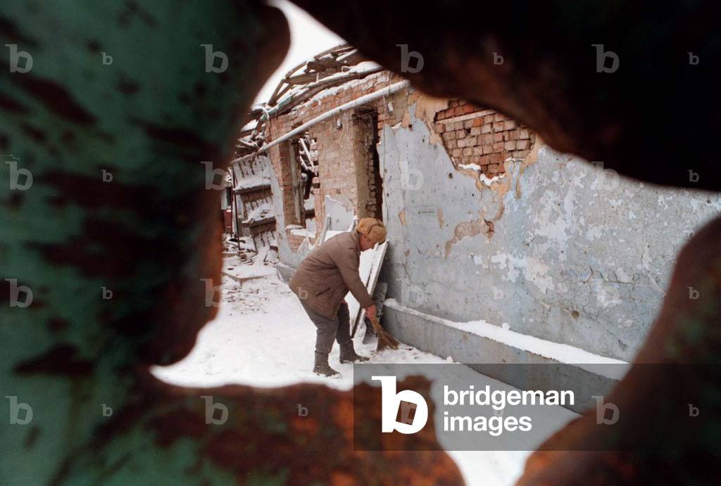Image of A CHECHEN MAN CLEANS THE BACKYARD OF HIS HOUSE IN