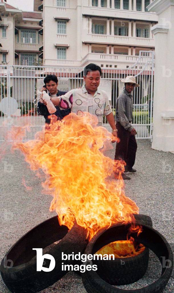 Image of A STRIKING HOTEL EMPLOYEE SETS TIRES ON FIRE OUTSIDE PHNOM