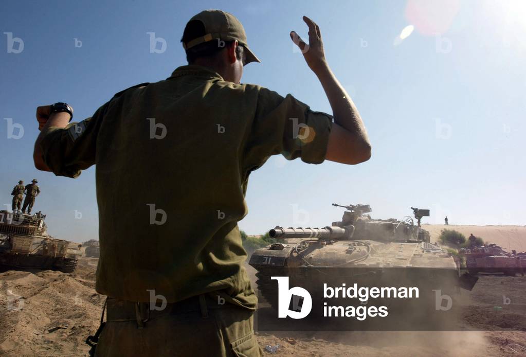 Image of AN ISRAELI SOLDIER DIRECTS A TANK NEAR THE EREZ CROSSING