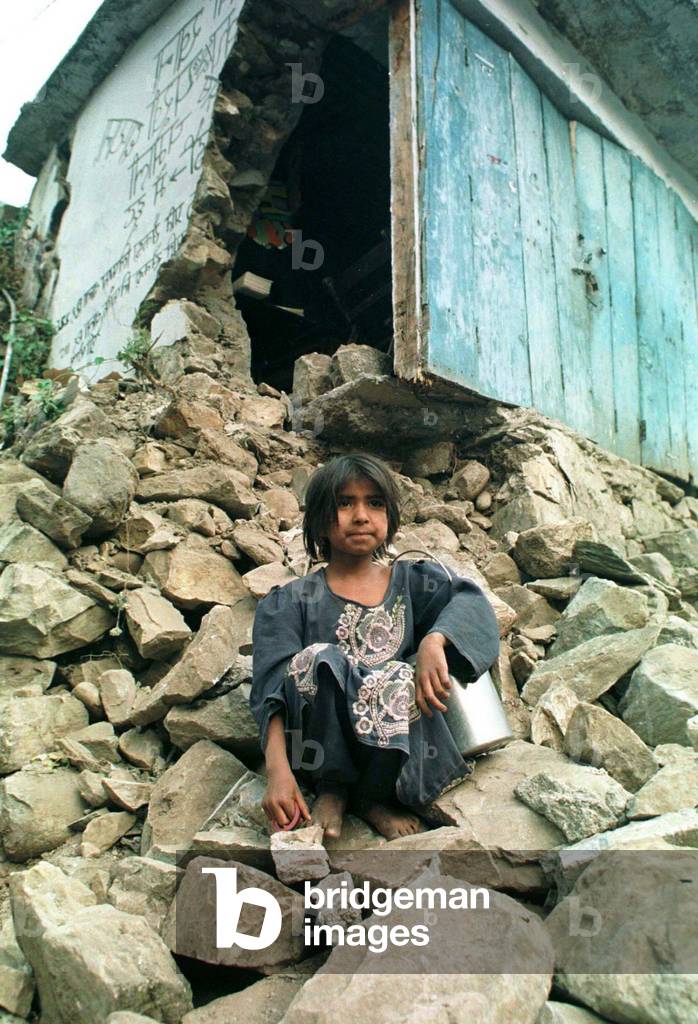 Image of A girl sits in front of her house in Chamoli