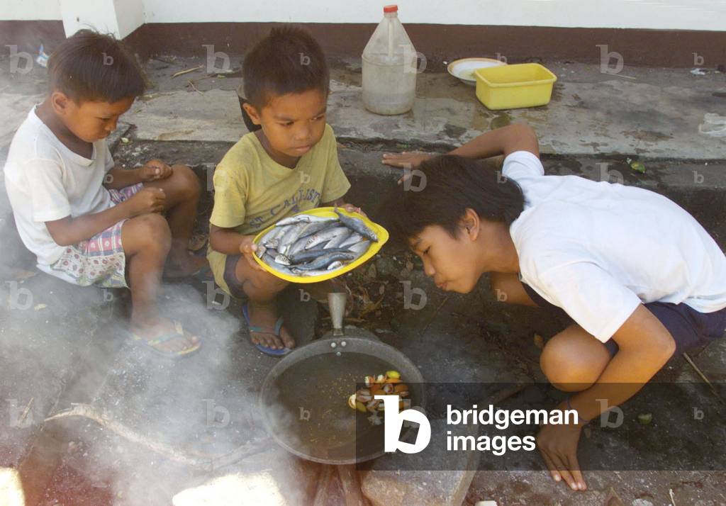 Image of FILIPINO VILLAGERS COOK THEIR FOOD AT AN EVACUATION CENTRE IN