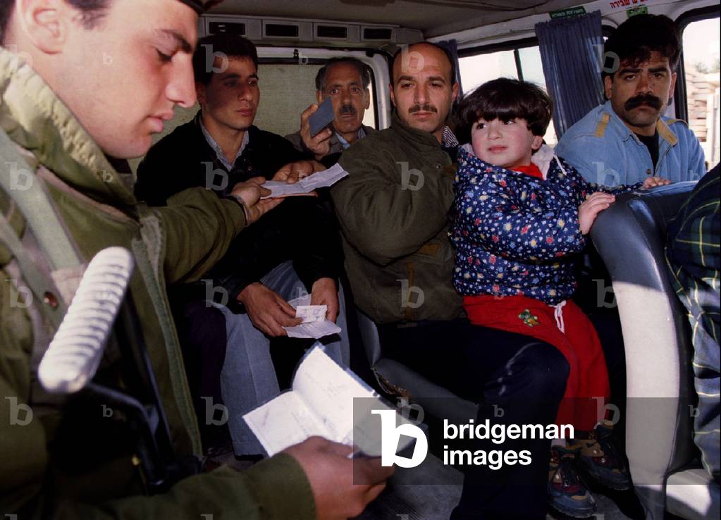 Image of An Israeli soldier checks the entry permits and identity cards