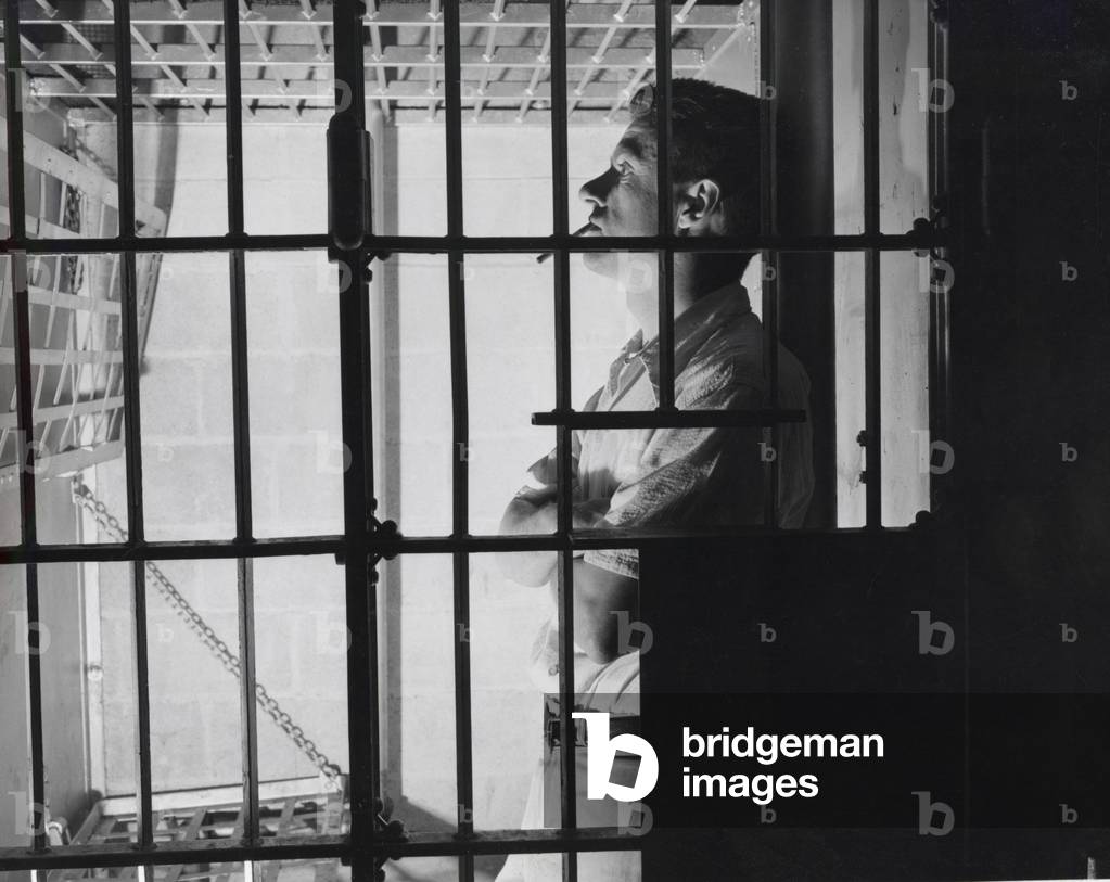 Side profile of a male prisoner smoking in a prison cell by