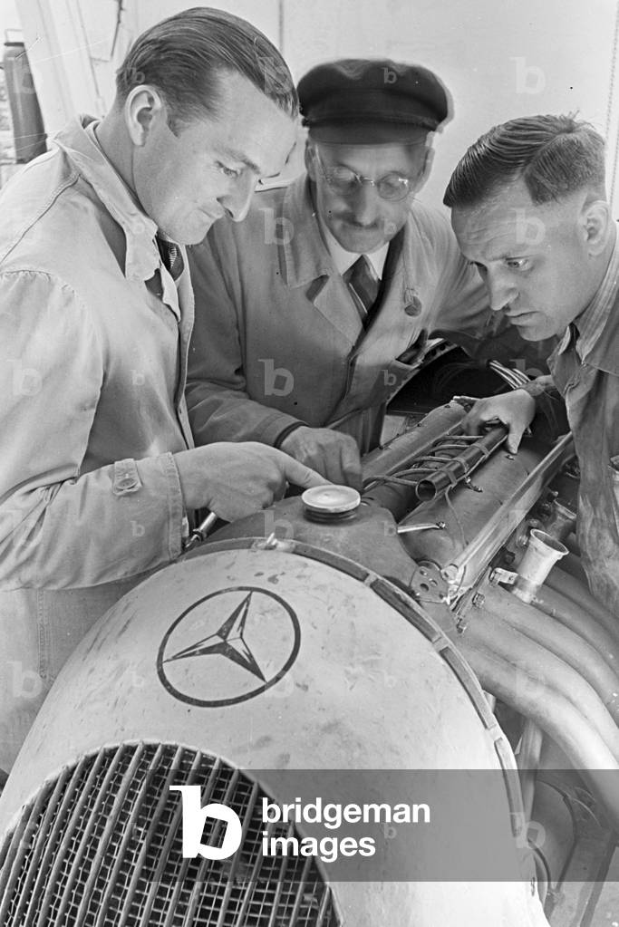 Image of The racing driver Hermann Lang talking to car mechanics in