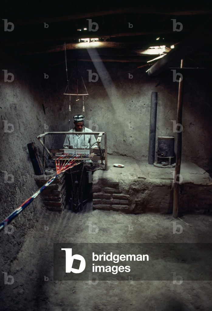 Image of A Uygur man weaves bright silk material in his mud by Wolinsky ...
