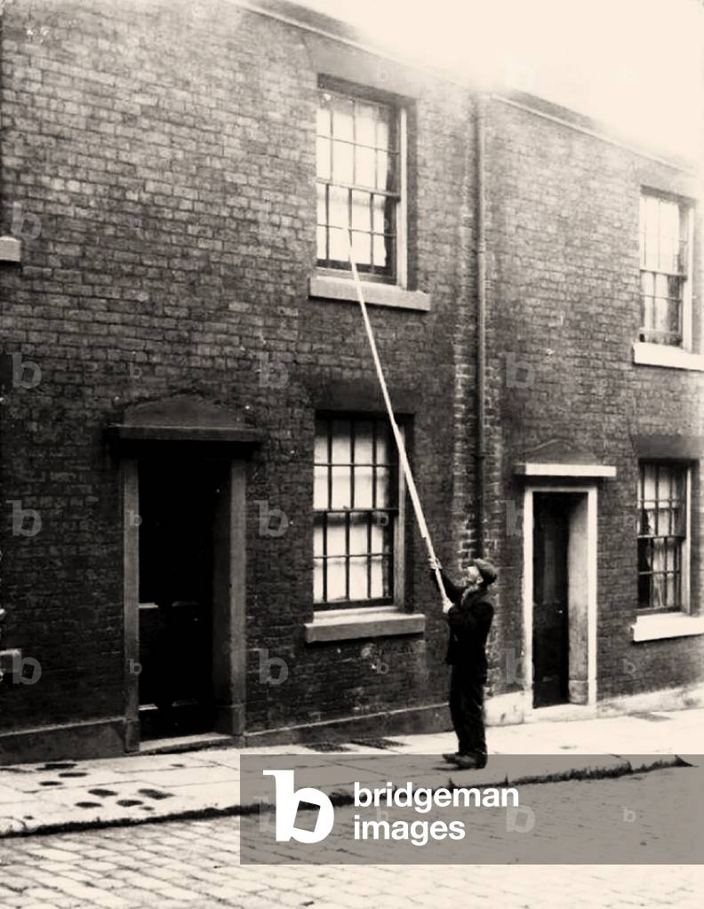 Image of A knocker Upper waking up a client, Manchester, UK c.1912