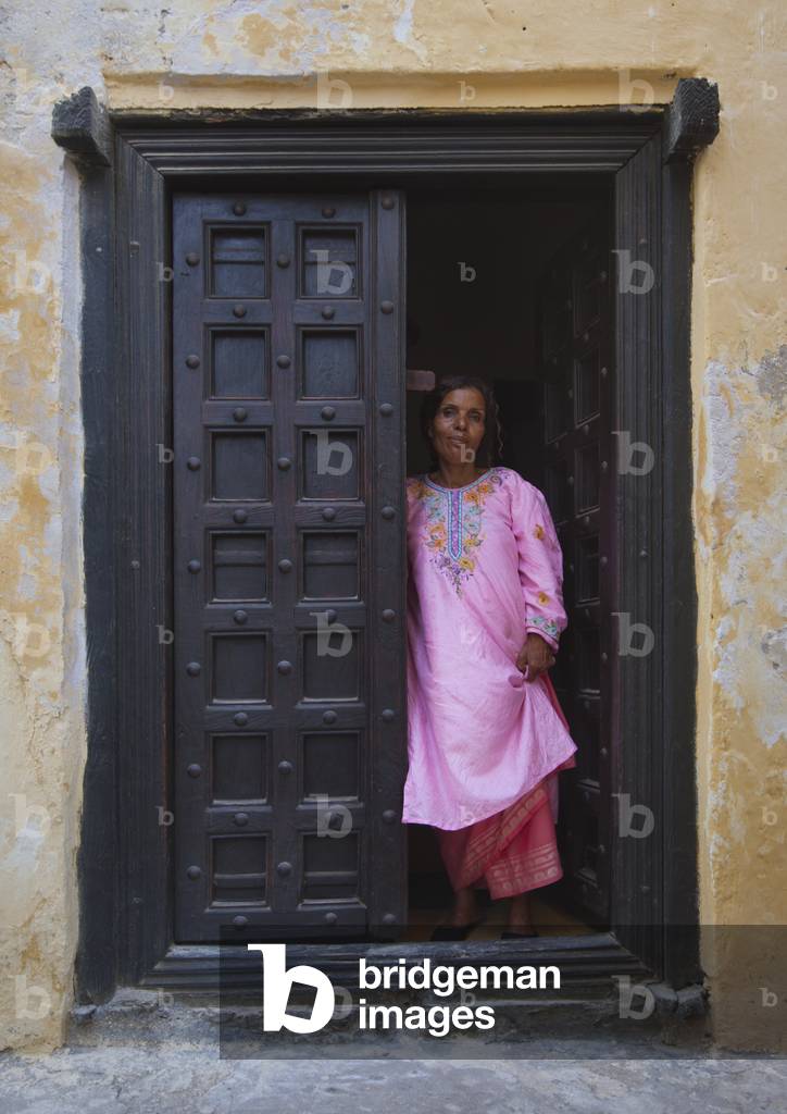 Image of Woman standing in the frame of omani wooden carved door,