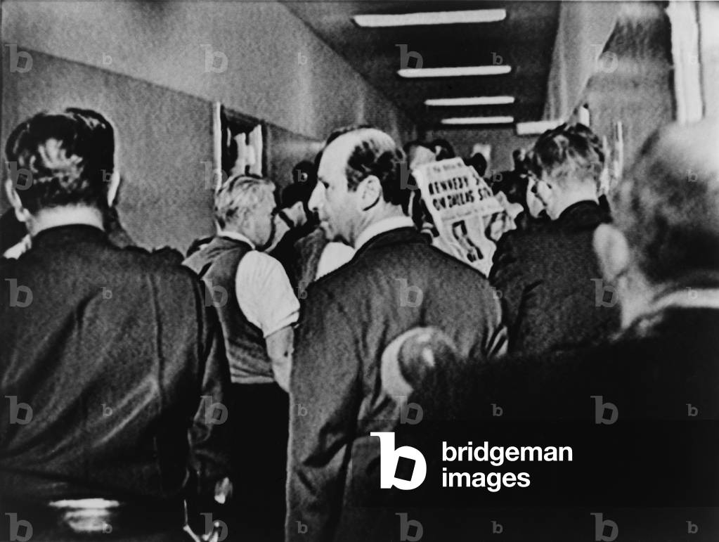 Image of Jack Ruby, (1911-1967), center, in the crowded hall at police
