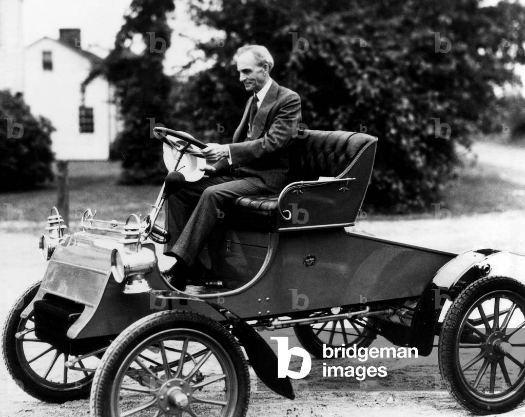 Image of Henry Ford, driving one of his earlier models, the 1903