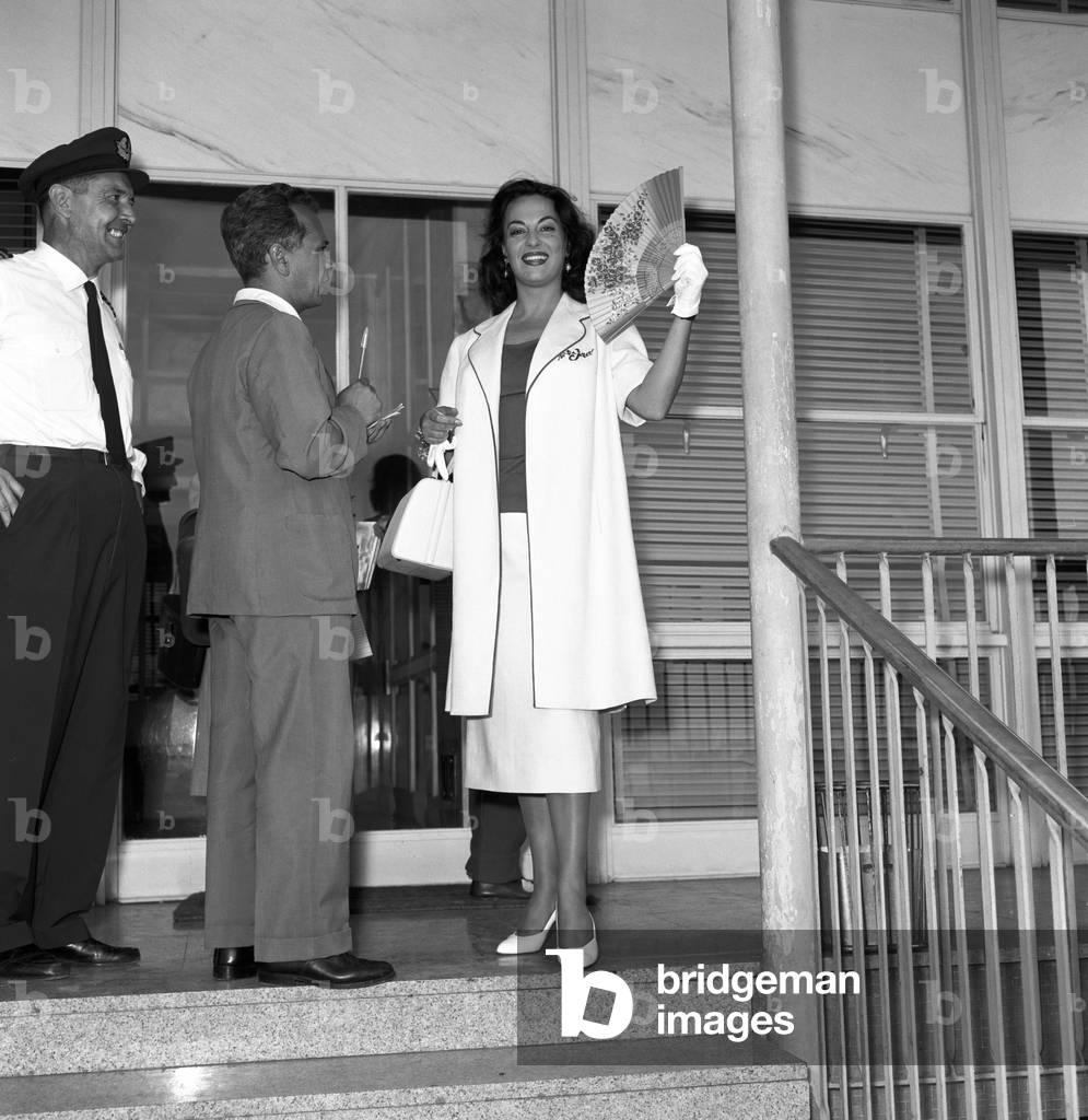 Image of Yvonne Sanson waving a fan, Italy, 1957 (b/w photo)