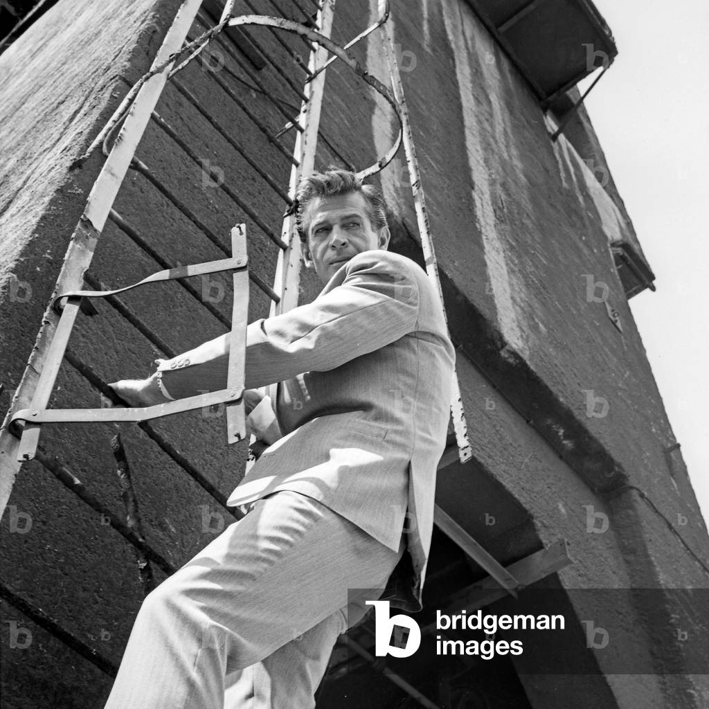 Image of American actor George Nader on a fire escape at Hamburg,