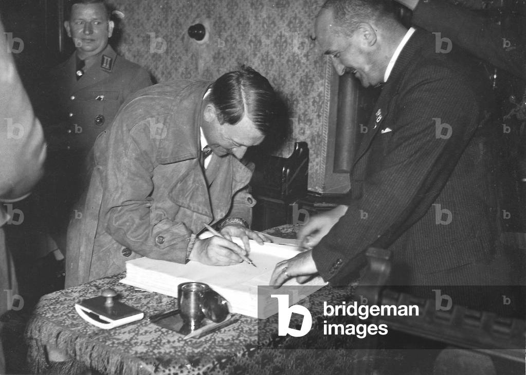 Image of Adolf HItler signs the Golden Book in Munich, 1935 (b/w