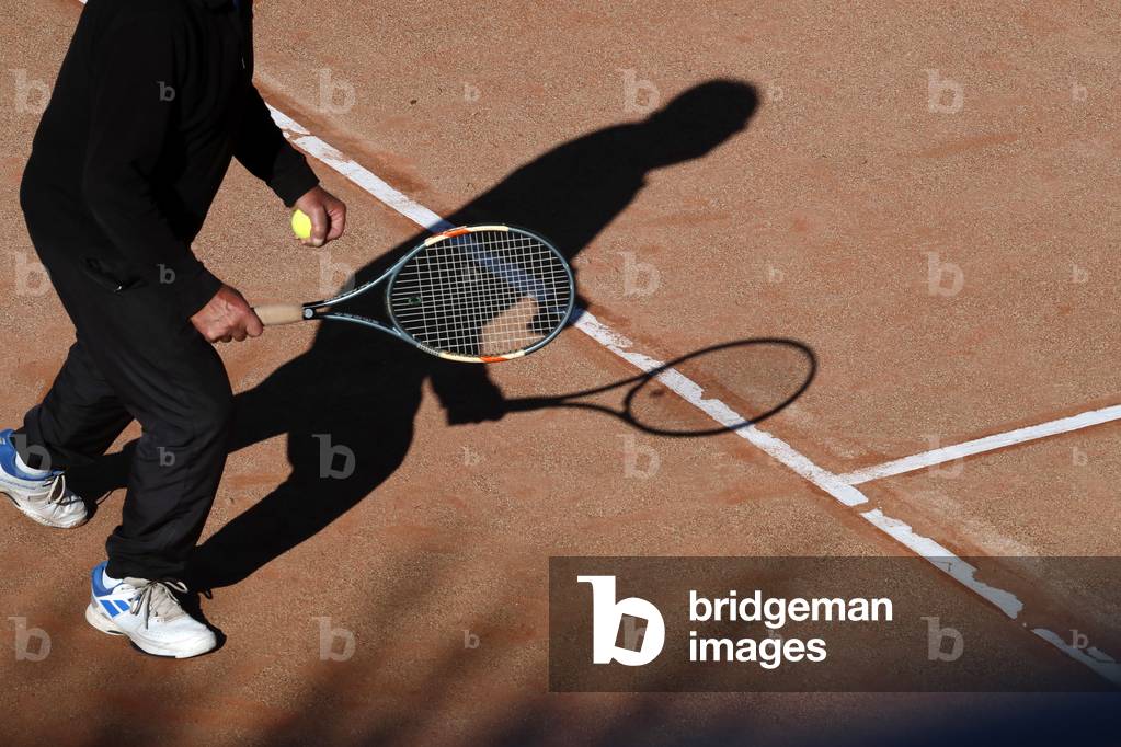 Image of Shadow of a male tennis player on red clay court,