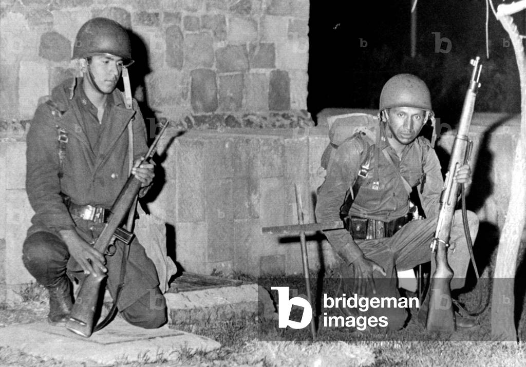 Image of Mexico City: Mexican soldiers kneel by cross-marked site where an