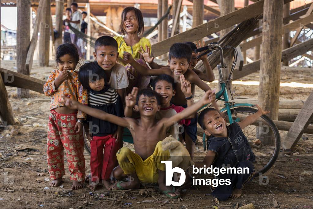 Image of Happy kids pose under the stilts of the village. Kompong by Galano, Salvo