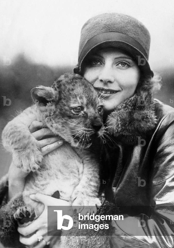 Image of Greta Garbo, holding a lion cub in her arms in