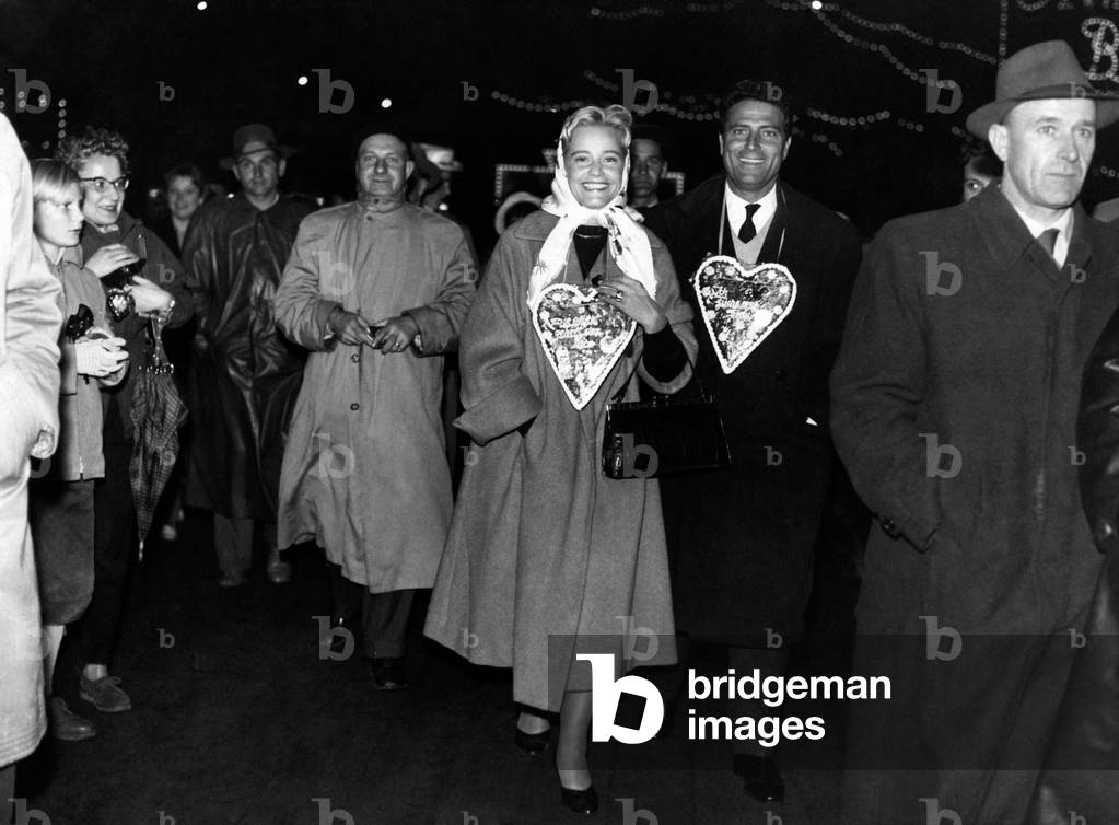 Image of Raf Vallone and Maria Schell strolling among the people, 1956