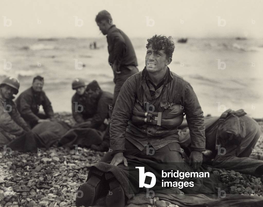 Image of World War II. American soldiers on Omaha Beach recovering the