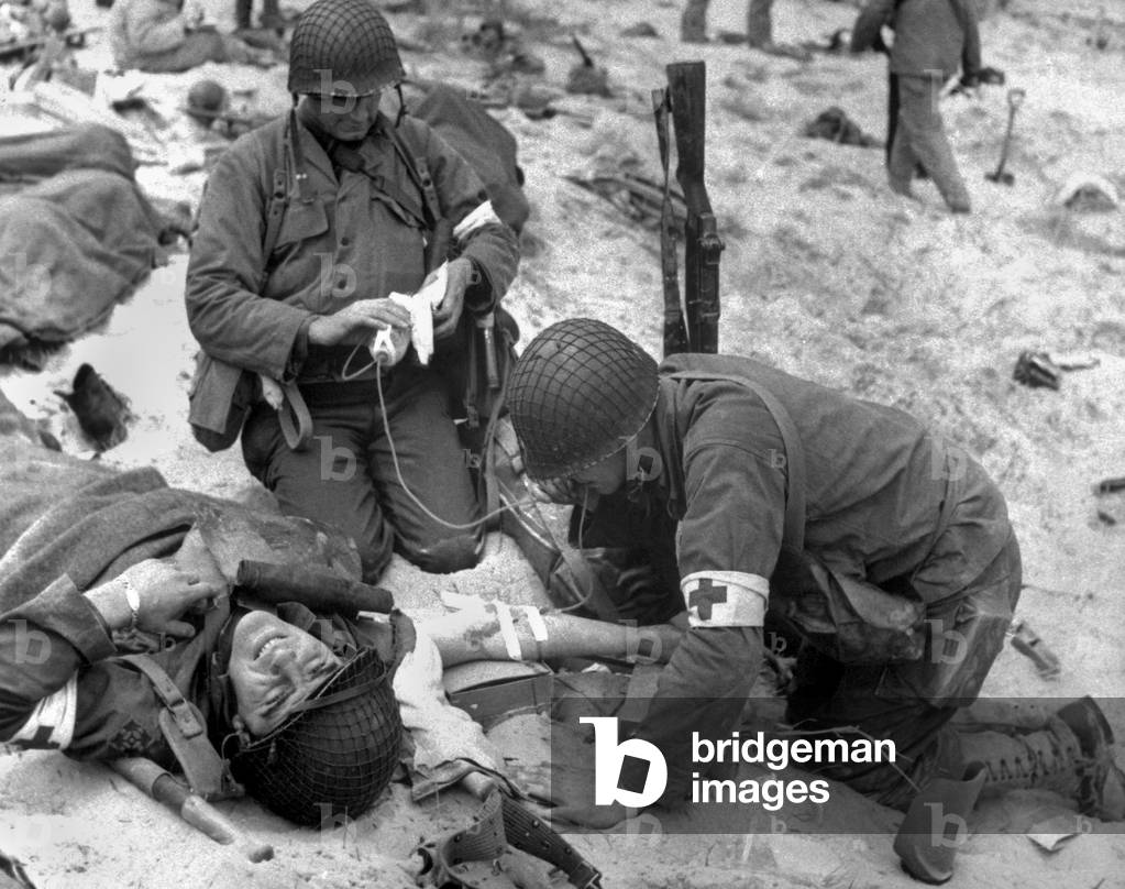 Image of Medics treat a wounded U.S. soldier on D-Day. During the