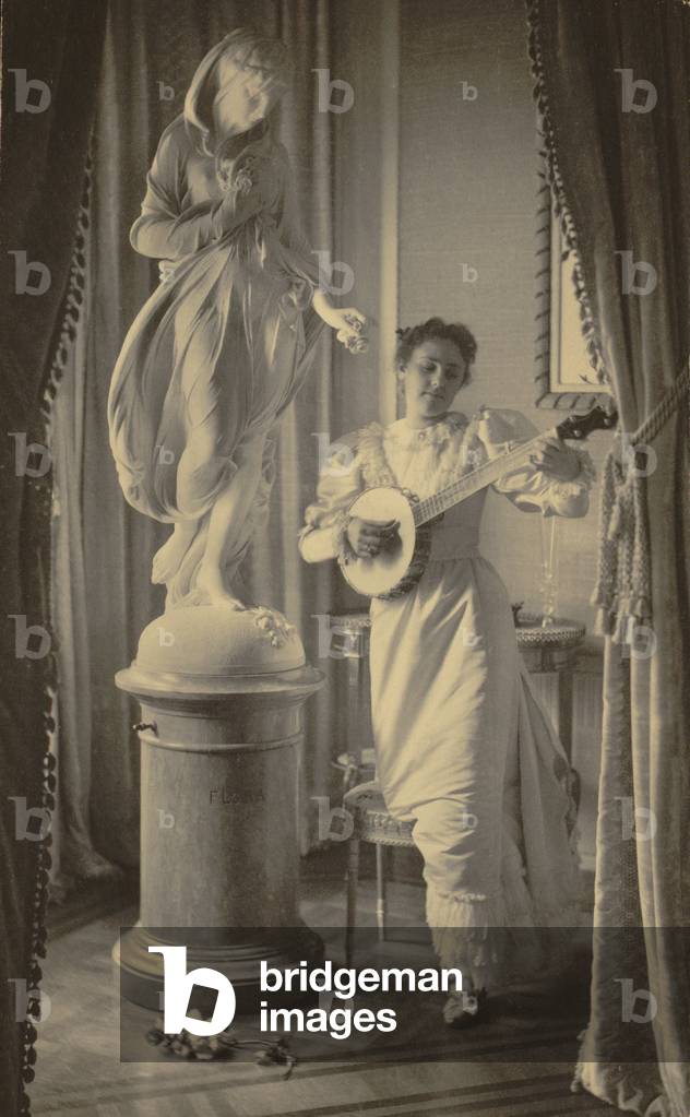 Image of Miss Apperson playing banjo beside statue of 'Flora' in Sen ...