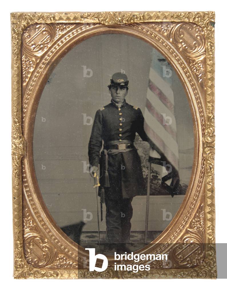 Image of A young Union officer poses with a with a flag